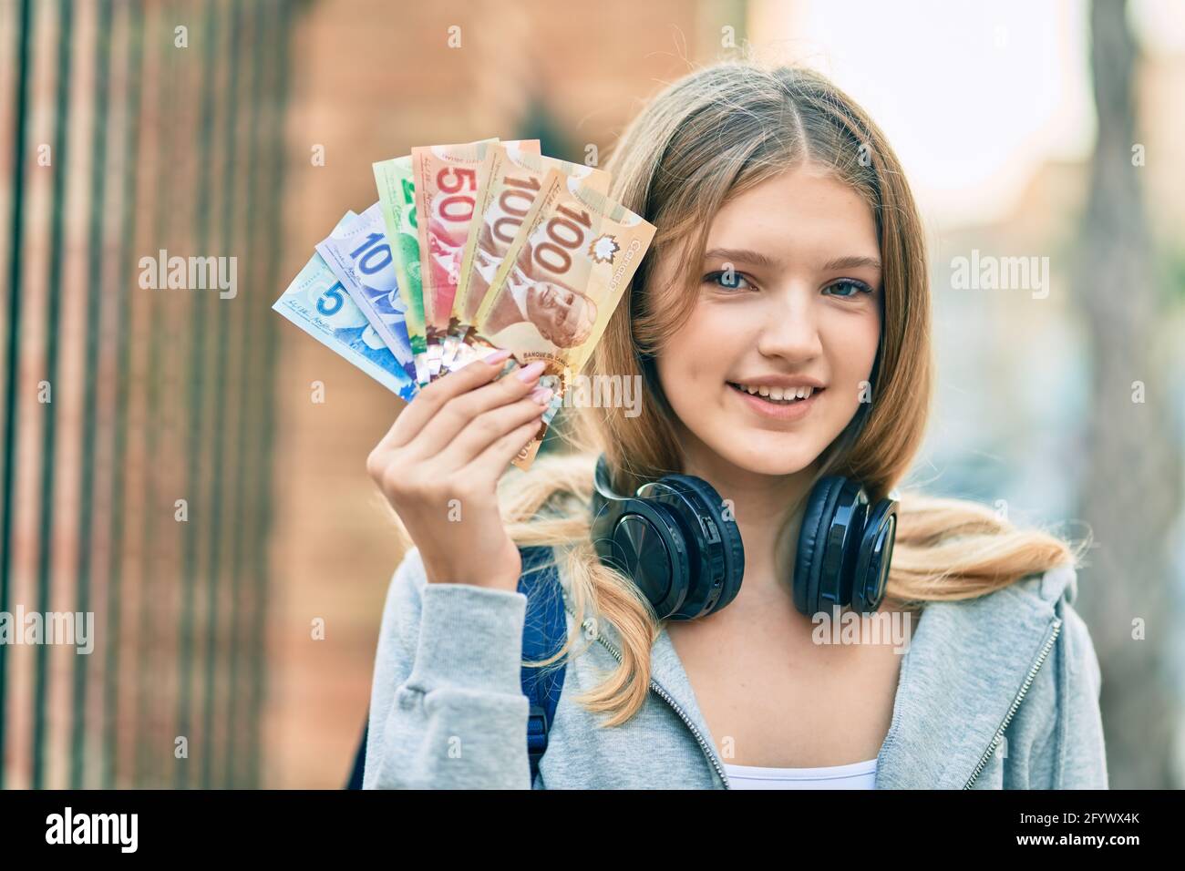 Beautiful caucasian student teenager using headphones holding canadian ...