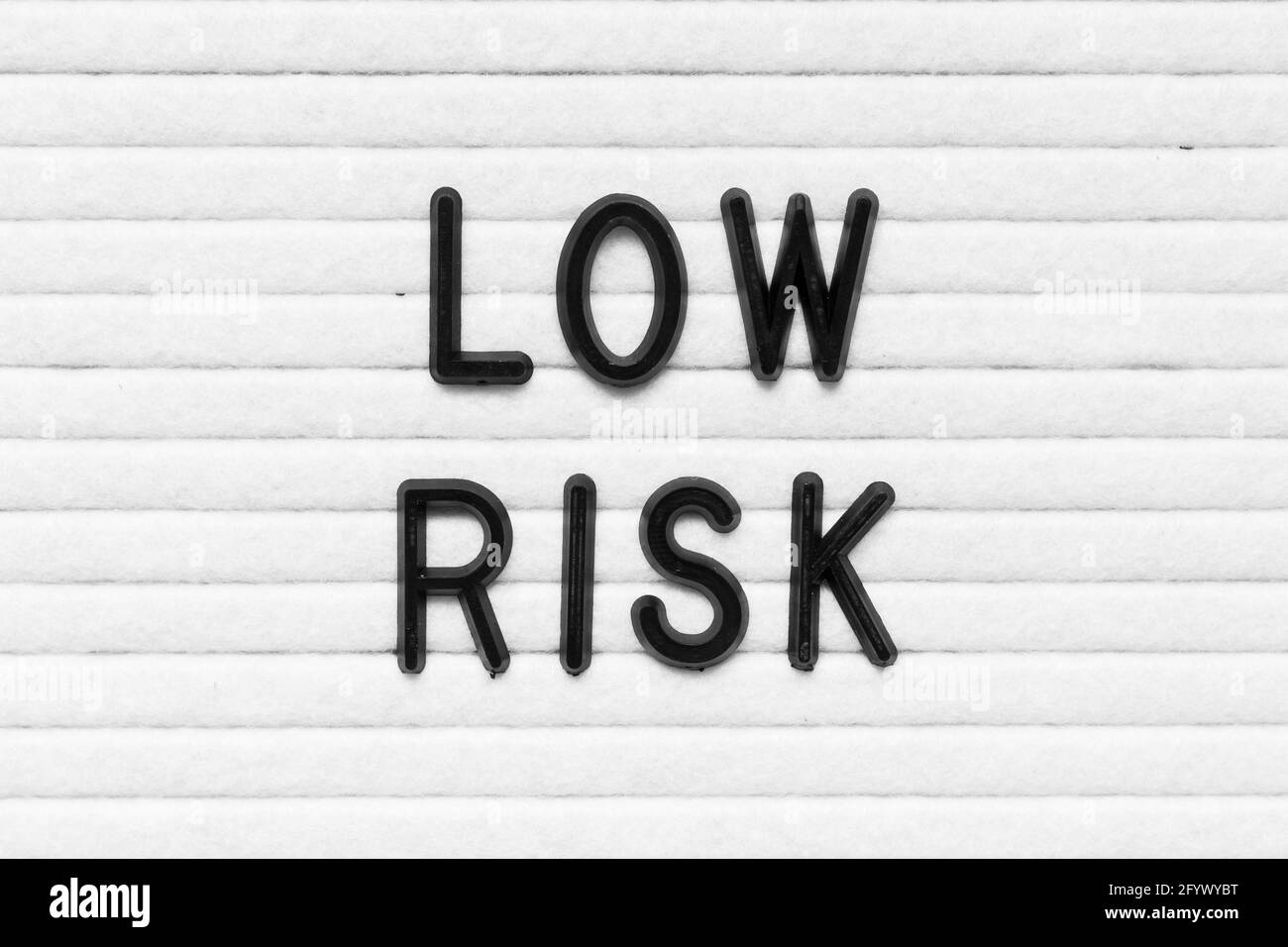 Black alphabet letter in word low risk on white felt board background ...