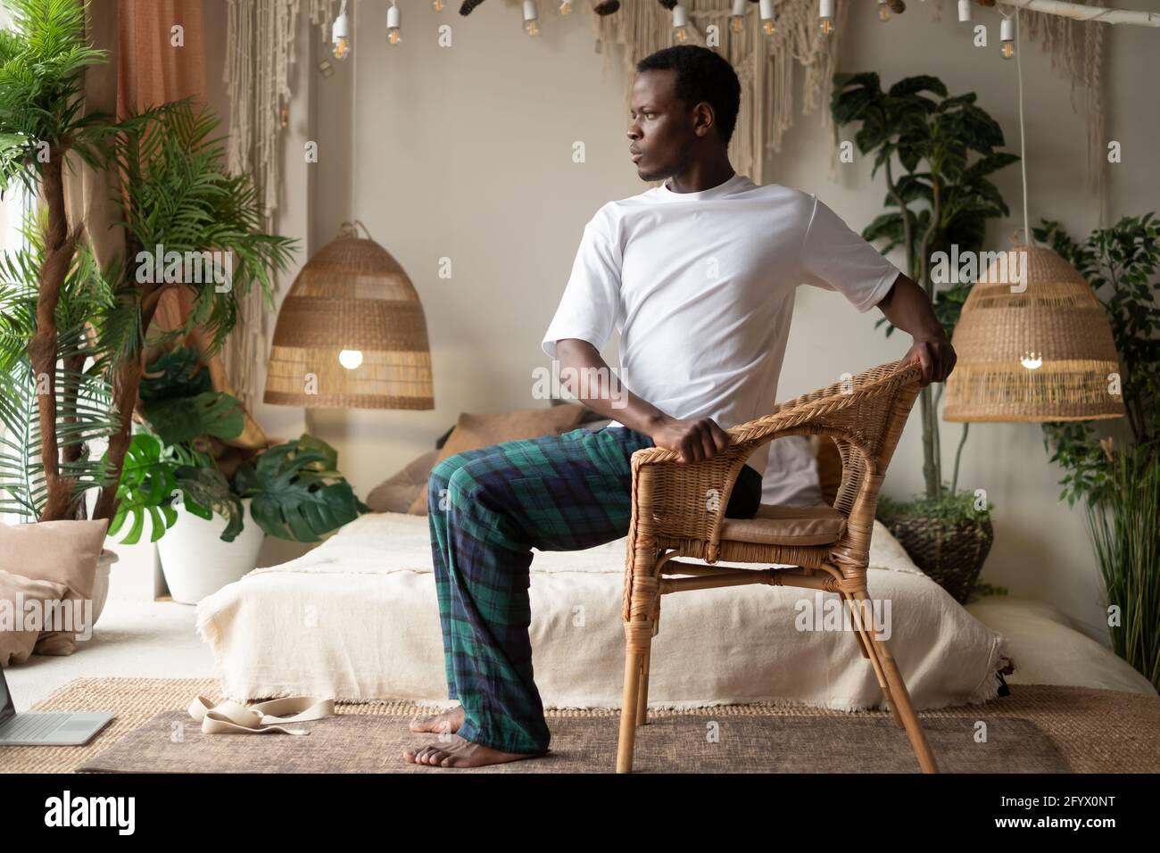 Sporty young african man practicing yoga using chair, doing Revolved ...