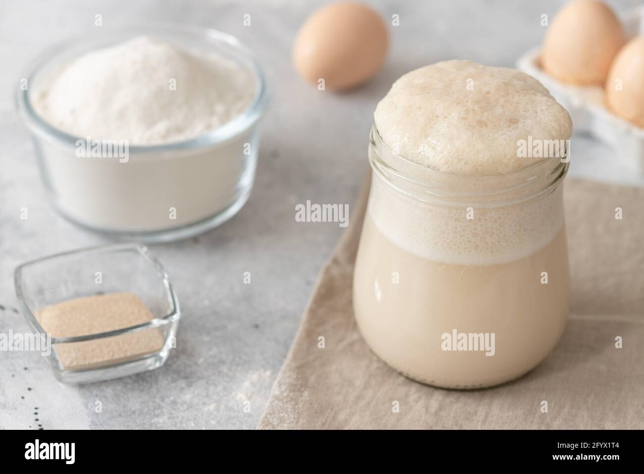close-up of fermented sourdough starter in glass jar on gray background ...