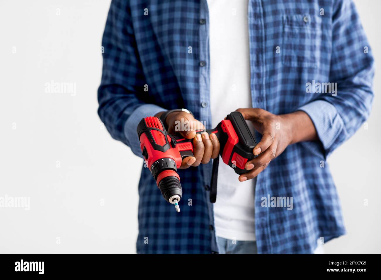 Instruments and accessories for assembling. Black man holding electric ...