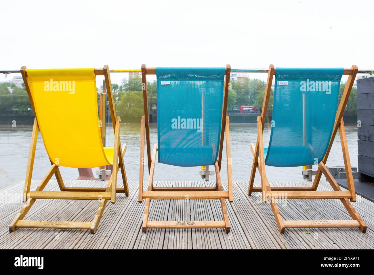 Coloured deckchairs by the river Stock Photo - Alamy