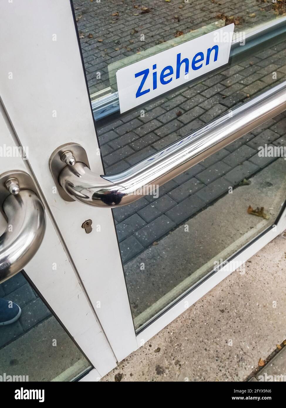 Elevated detail view of a locked shop door with a white sign and the ...
