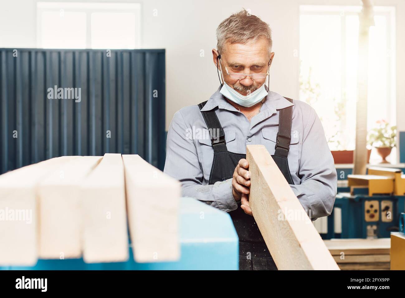 Portrait of an elderly carpenter or carpenter in overalls working with ...