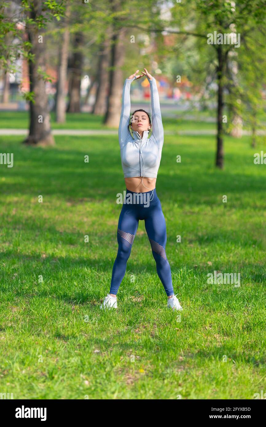 Young woman stretching body - warming up before running or working out ...