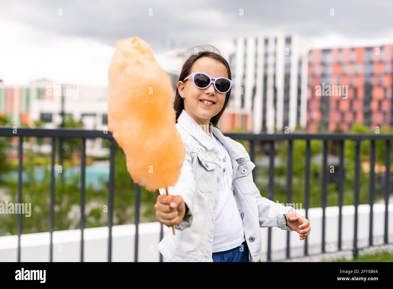 Adorable little girl eating candy-floss outdoors at summer Stock Photo ...