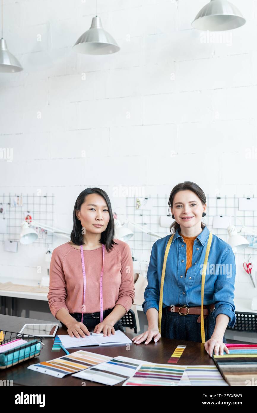 Two young successful businesswomen working over fashion collection in ...