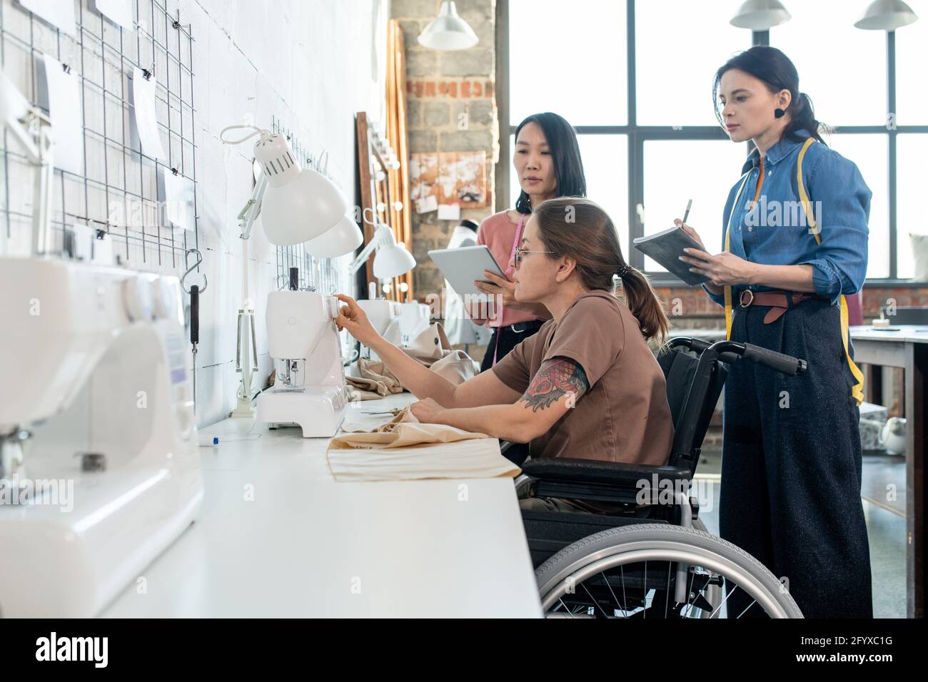 Two fashion designers standing by seamstress during teamwork Stock ...