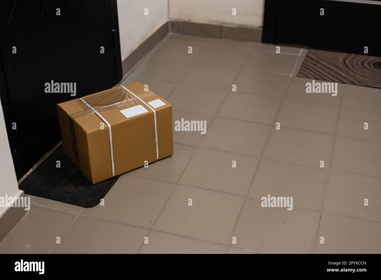 Cardboard box on rug near entrance door Stock Photo - Alamy