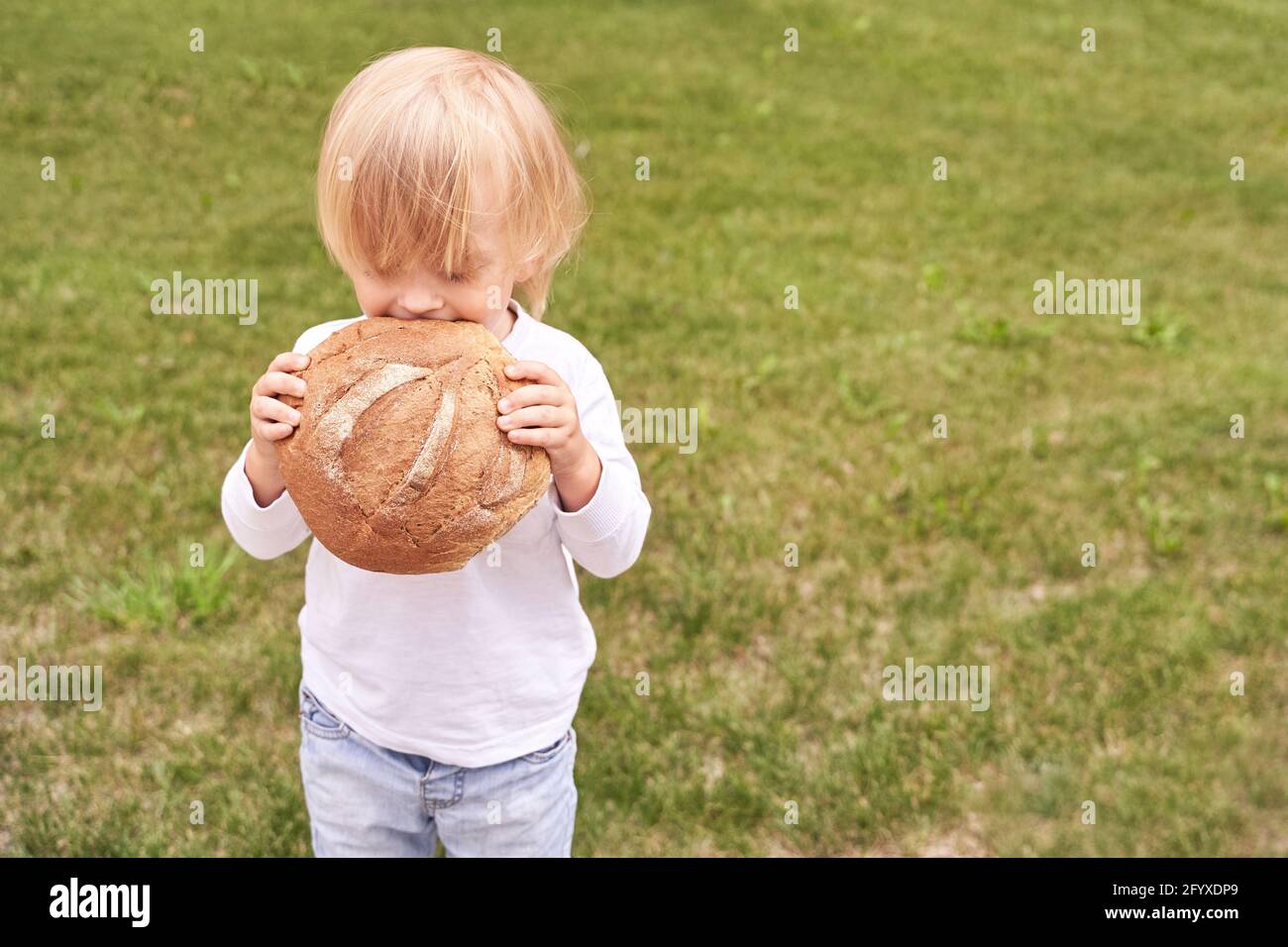 Child holds and bite round bread. Healthy food Stock Photo - Alamy