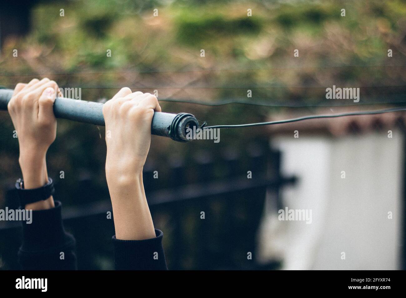 detail of hands clinging to a clothes hanger tube with unfocused ...