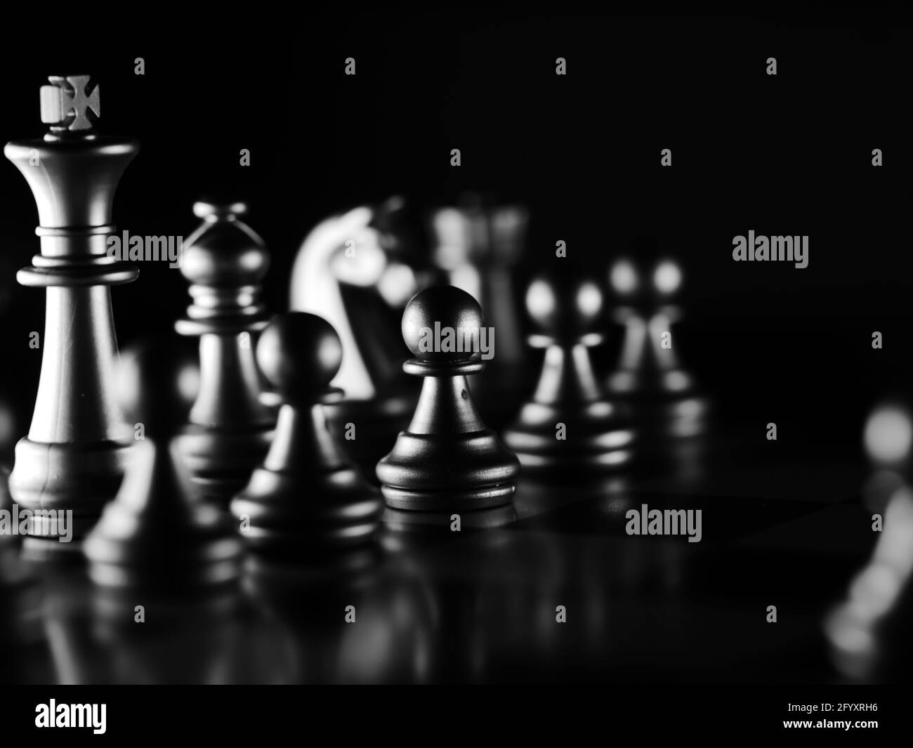A dramatic grayscale shot of chess figures lit in the darkness Stock ...
