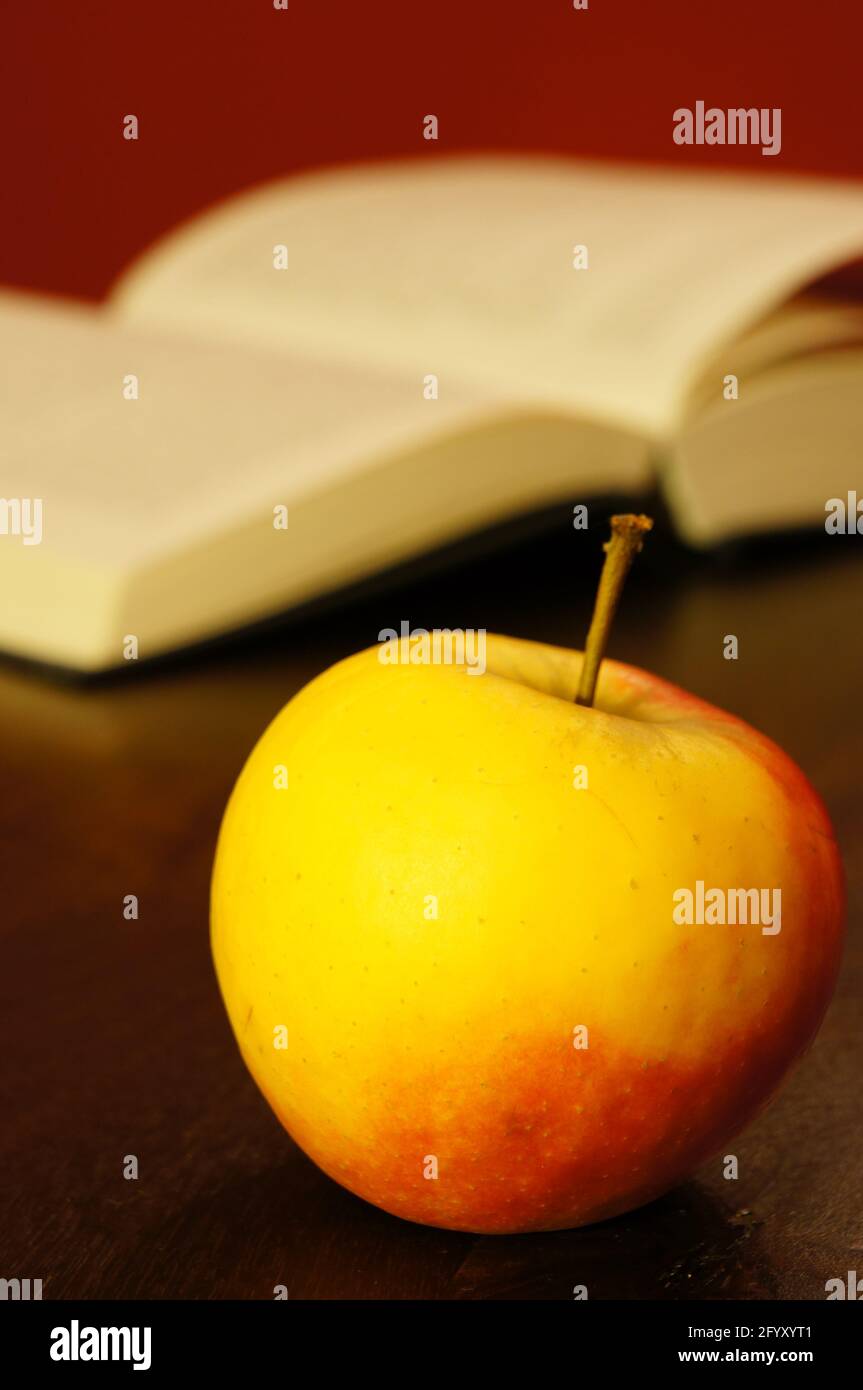 A vertical shot of a juicy apple on an open book background Stock Photo ...
