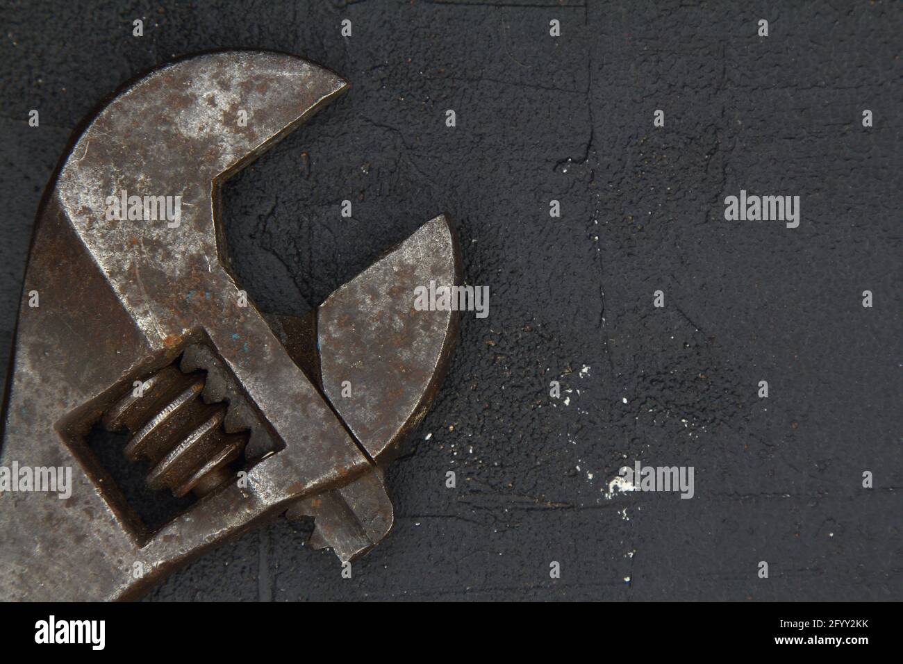 Old adjustable wrench on rusty metal sheet. Sliding forged wrench ...