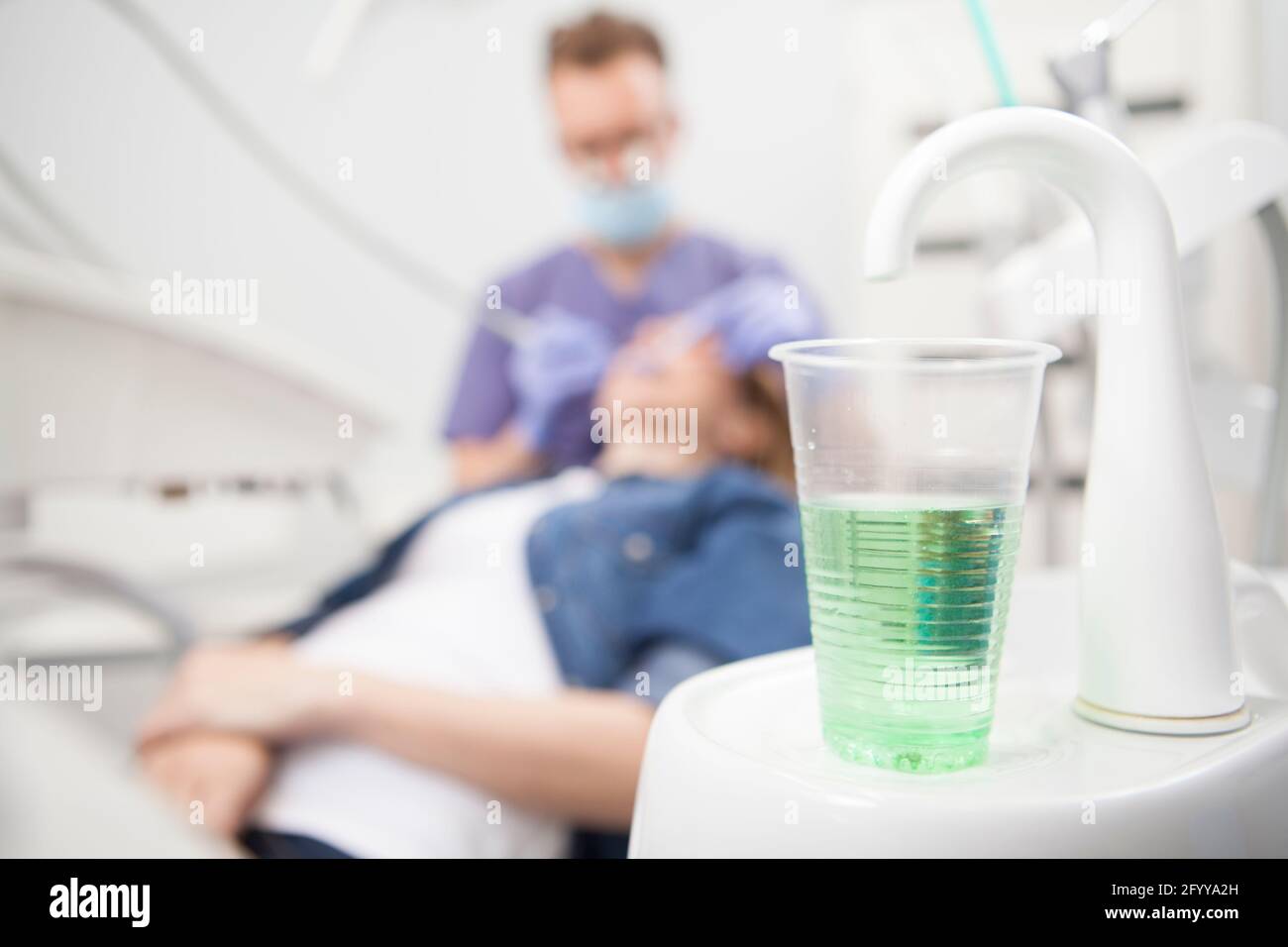 Selective focus on green mouth wash in a cup on dental tap sink ...
