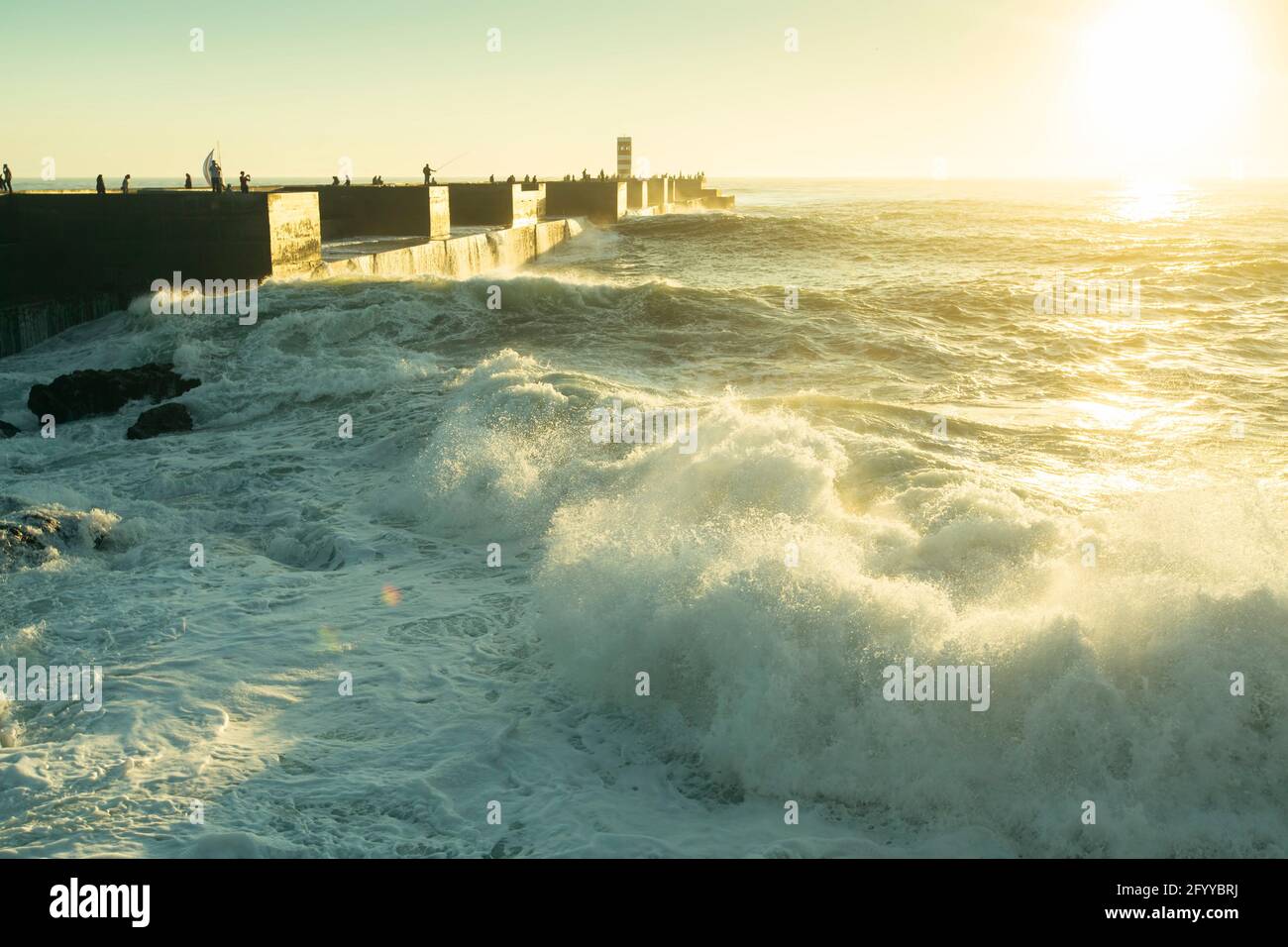 Atlantic pier with a wave of surf at sunset Stock Photo - Alamy