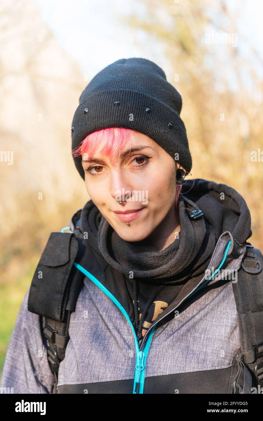 Positive female explorer wearing hat and outerwear with backpack ...