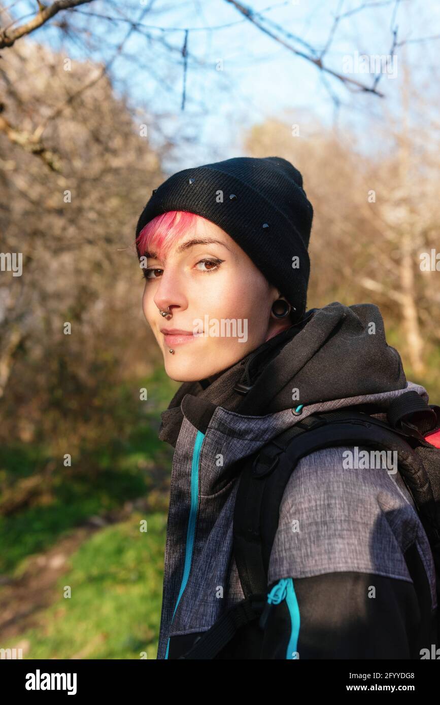Positive female explorer wearing hat and outerwear with backpack ...