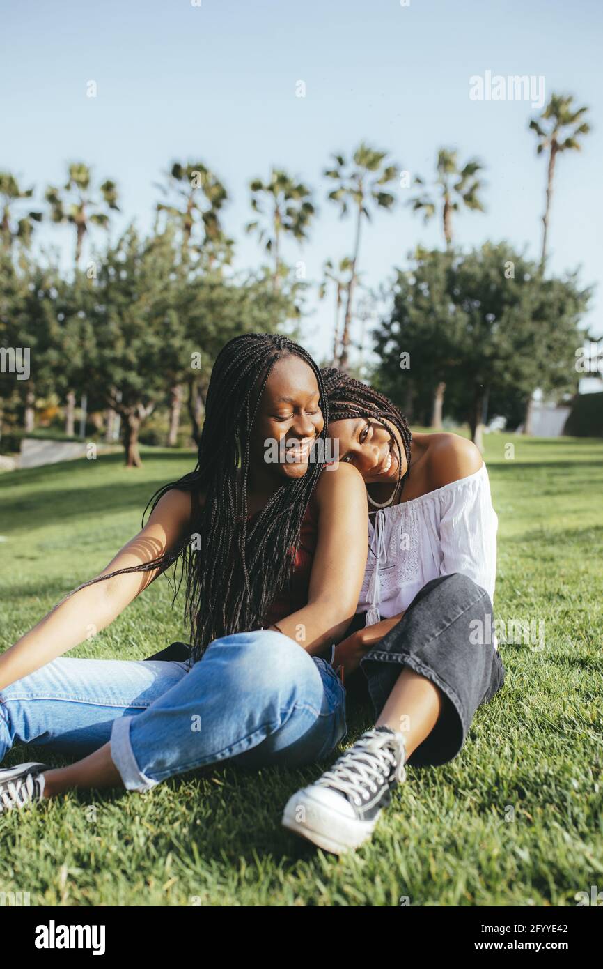 Full body of calm African American female friends cuddling and looking ...