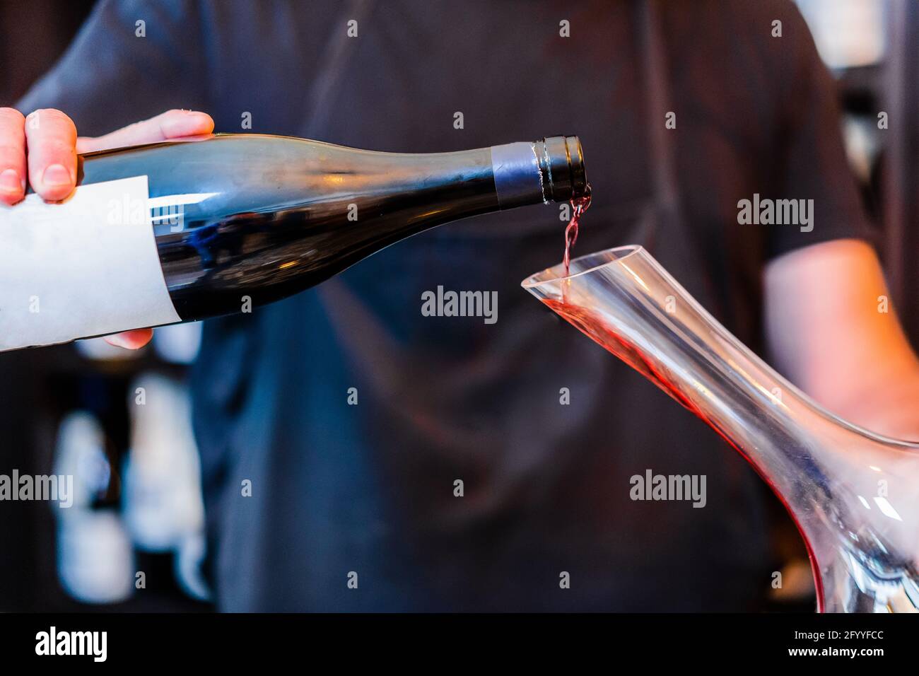 crop man sommelier in black apron standing at bar counter and pouring ...