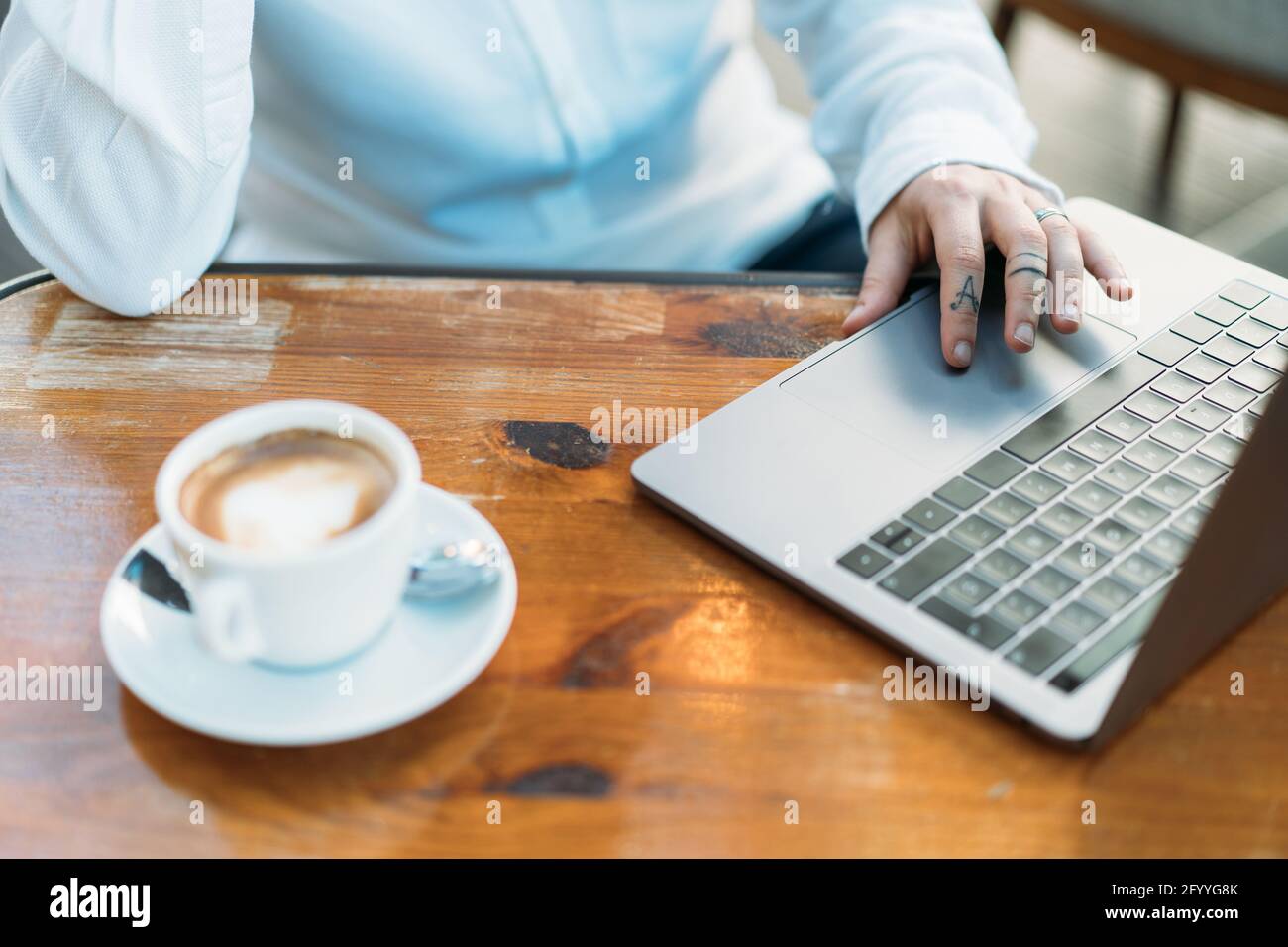 High angle of crop anonymous teleworker sitting at wooden table with ...