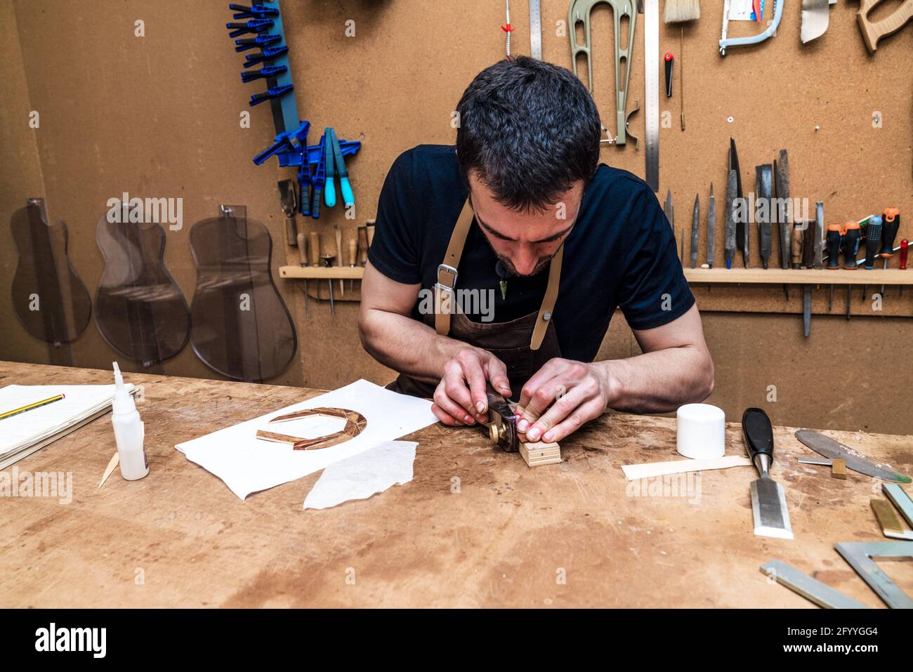 Focus unshaven male artisan flattening wooden block with manual tool at ...