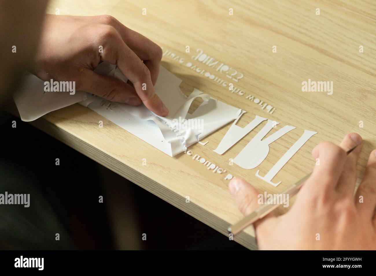 Crop faceless person transferring white cutout letters on transparent ...