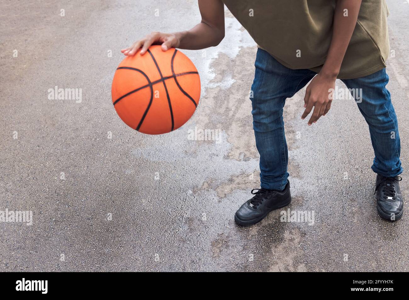 High angle of crop African American male dribbling basketball while ...