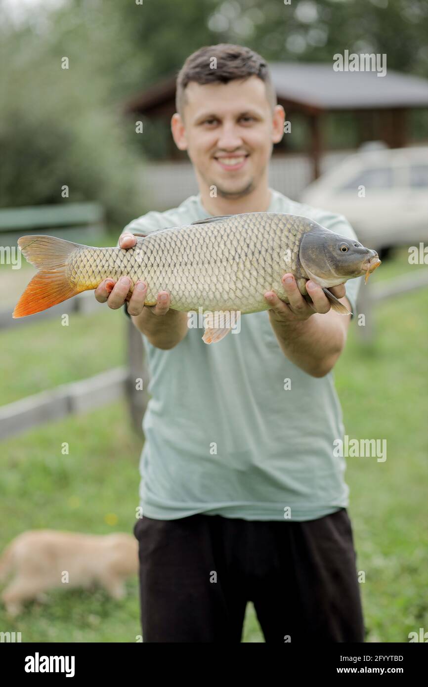 Happy angler holds trophy carp. Man with carp fish. Outdoors activities ...