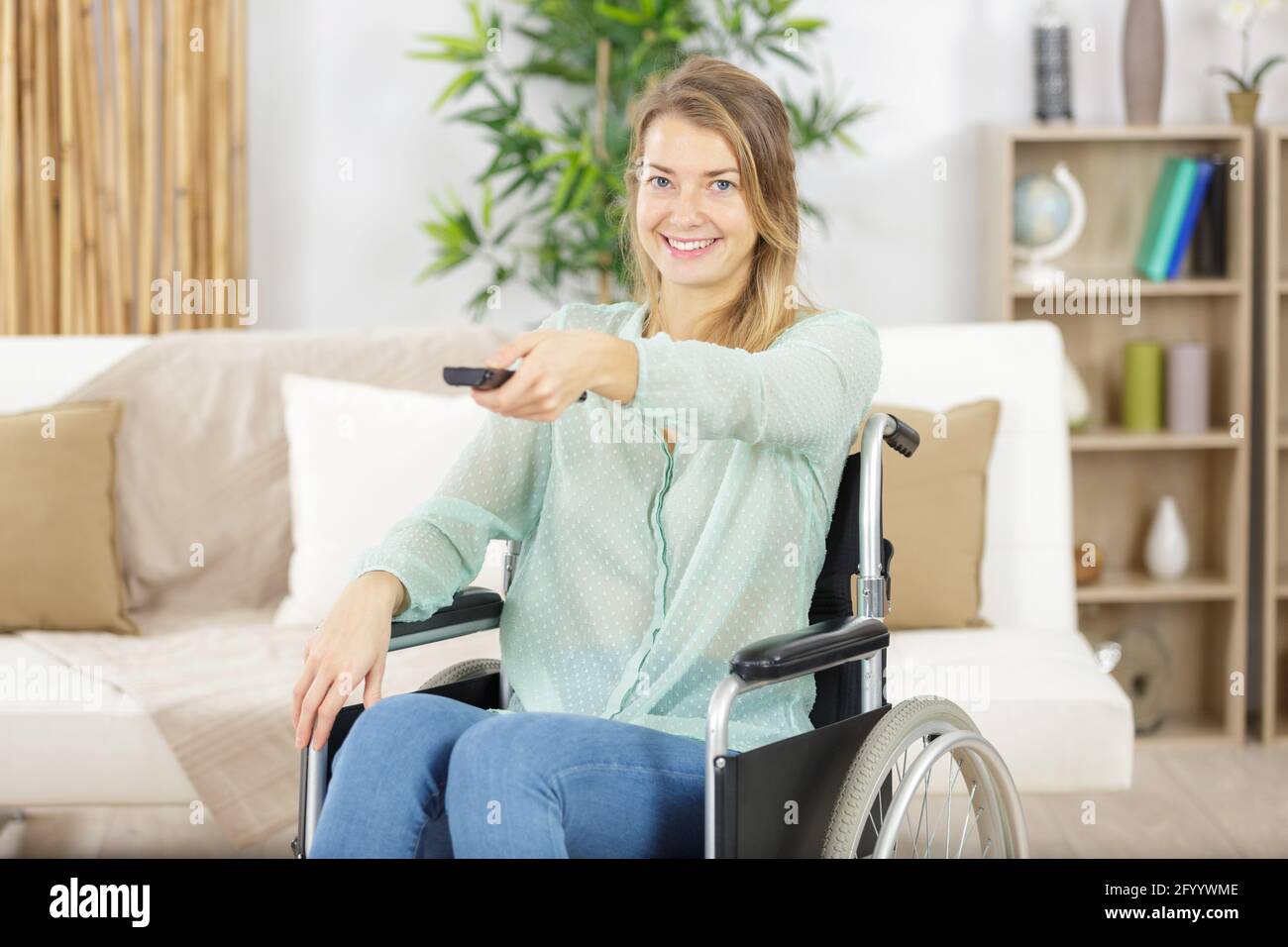 happy disabled young woman in wheelchair watching tv Stock Photo - Alamy