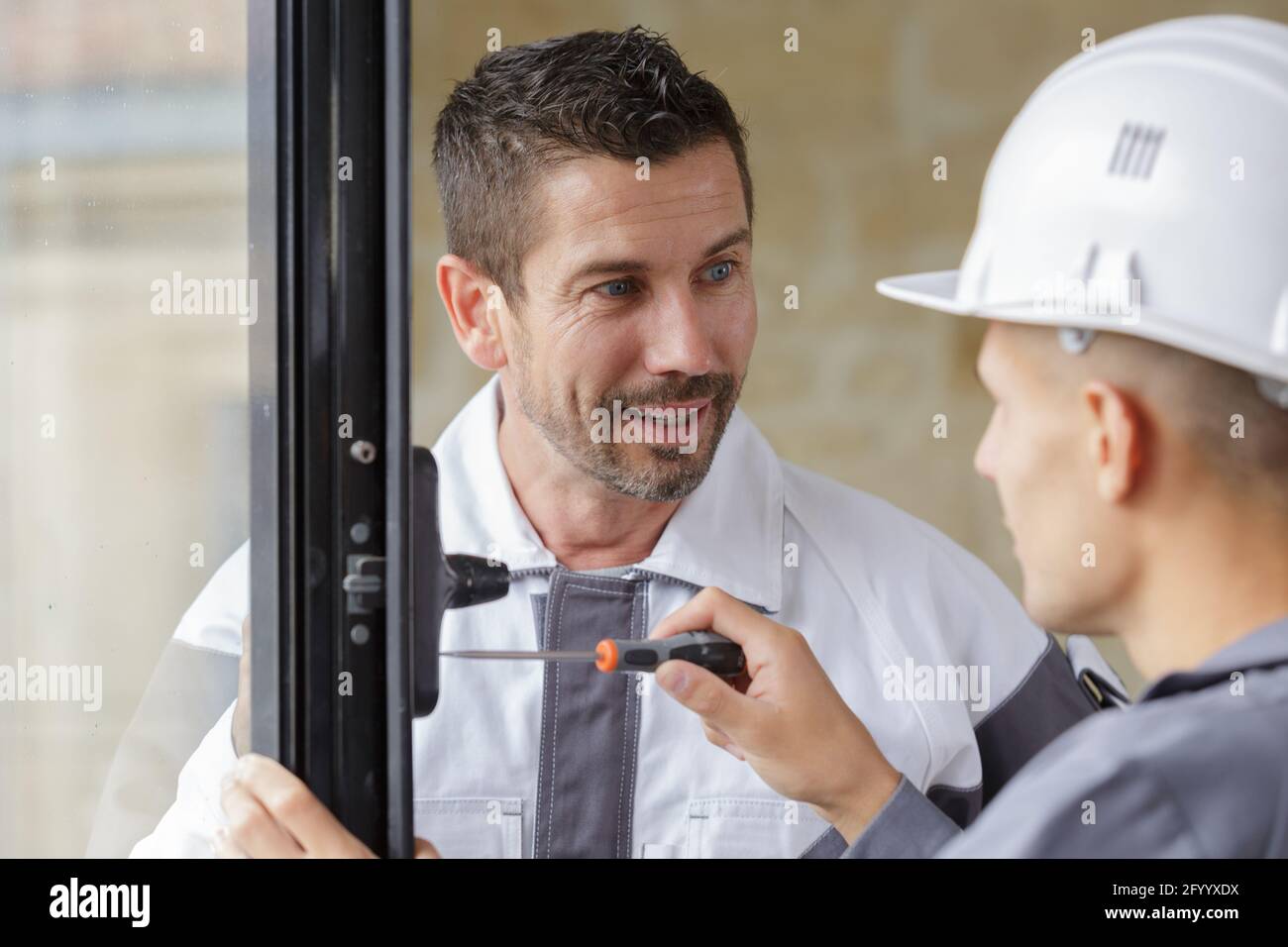 apprentice window fitter working under supervision Stock Photo - Alamy