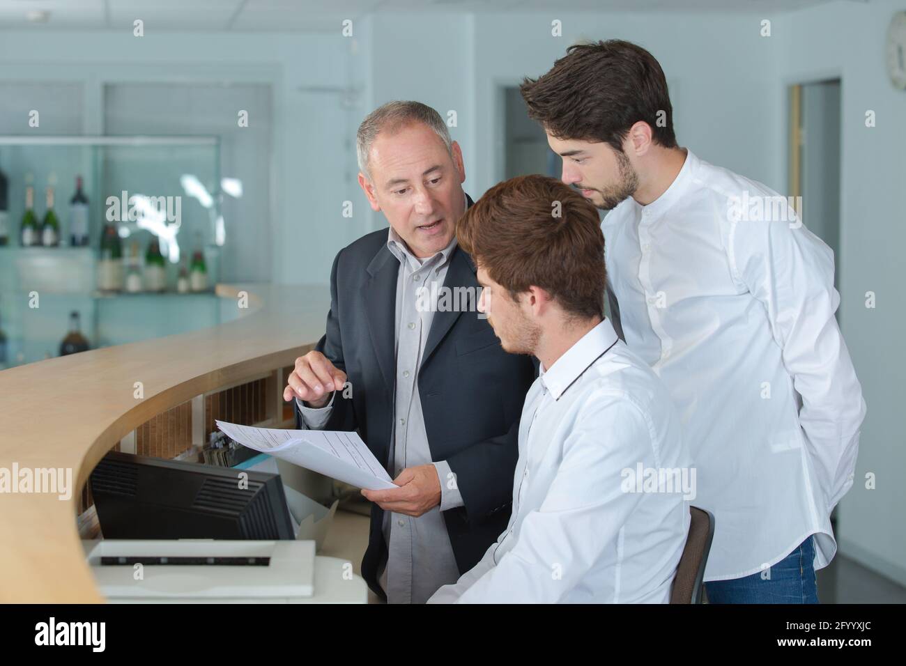 young men being trained at reception desk Stock Photo - Alamy