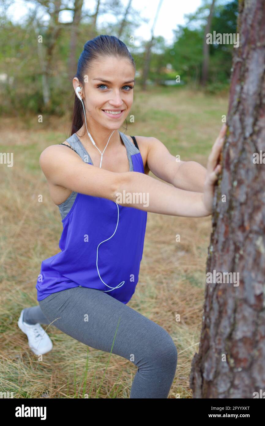 woman leaning against tree to stretch leg muscles Stock Photo - Alamy