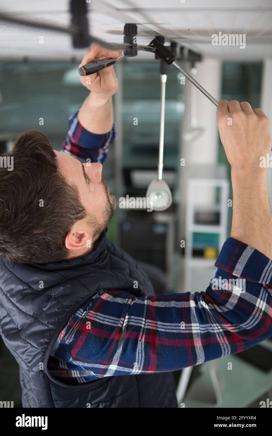 portrait of a male electrician fixing light on ceiling Stock Photo - Alamy