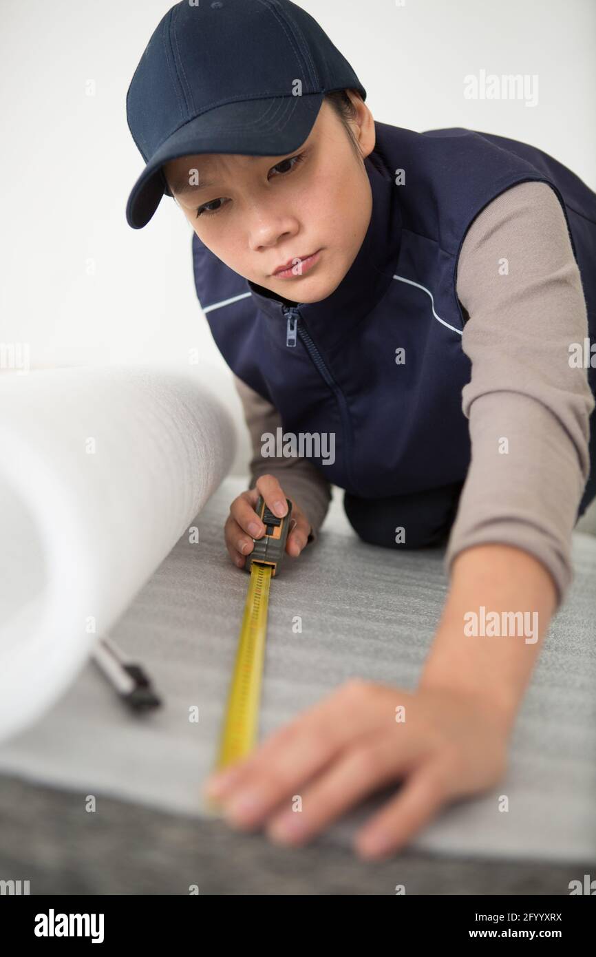 young woman in work overalls holding a tensioned tape measure Stock ...