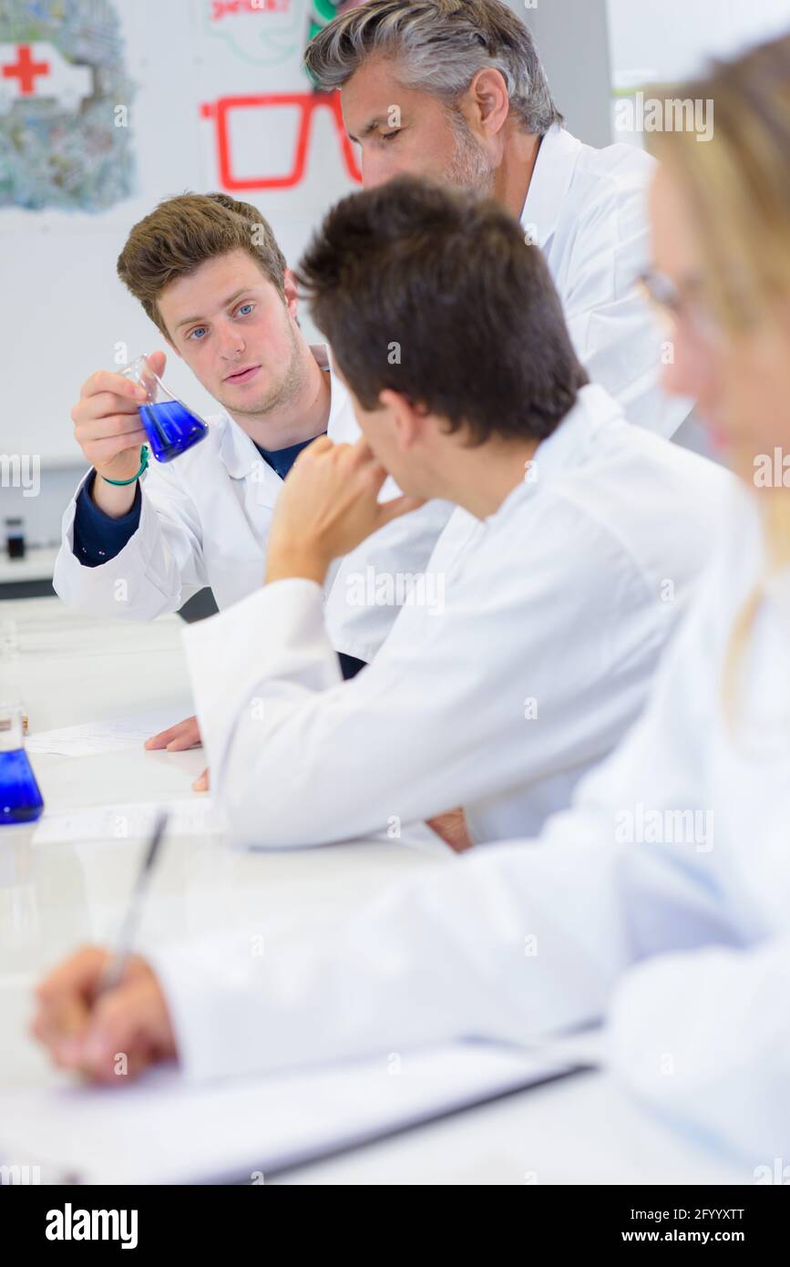 Student showing glass flask to classmate Stock Photo - Alamy