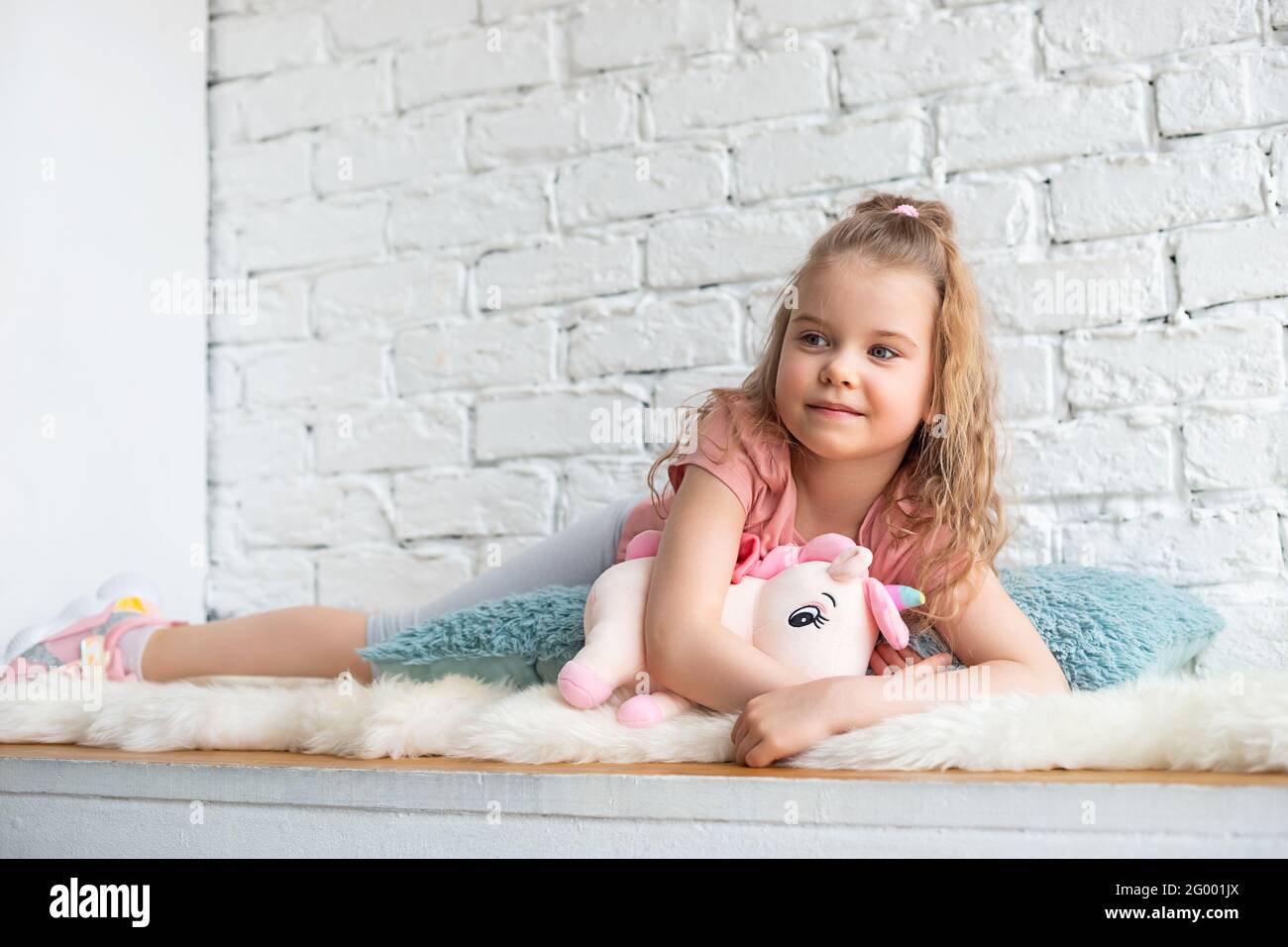 Portrait of preschool-aged caucasian girl lies on a fluffy rug on the ...