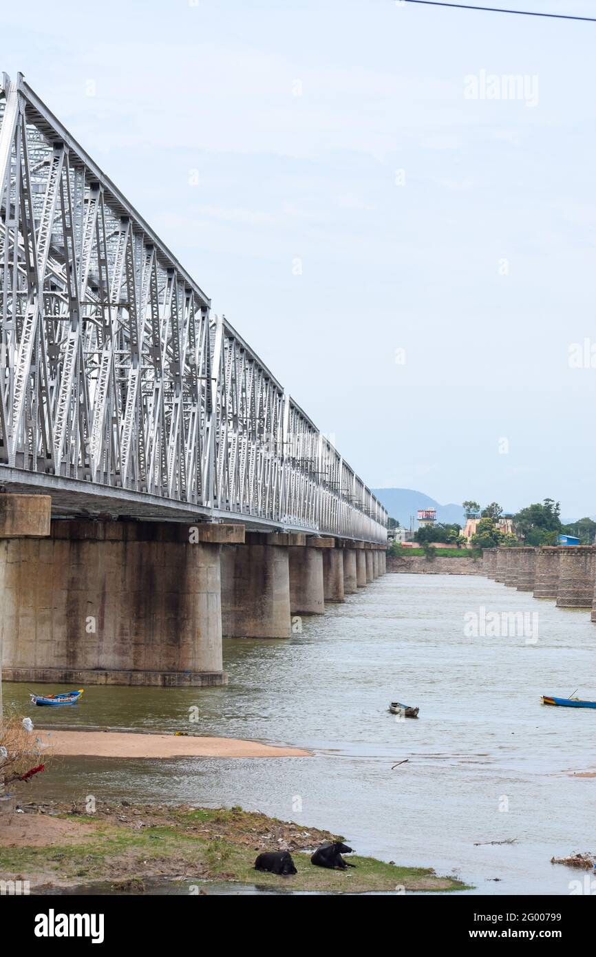 A vertical shot of a trestle bridge surrounded by a pond under a cloudy ...