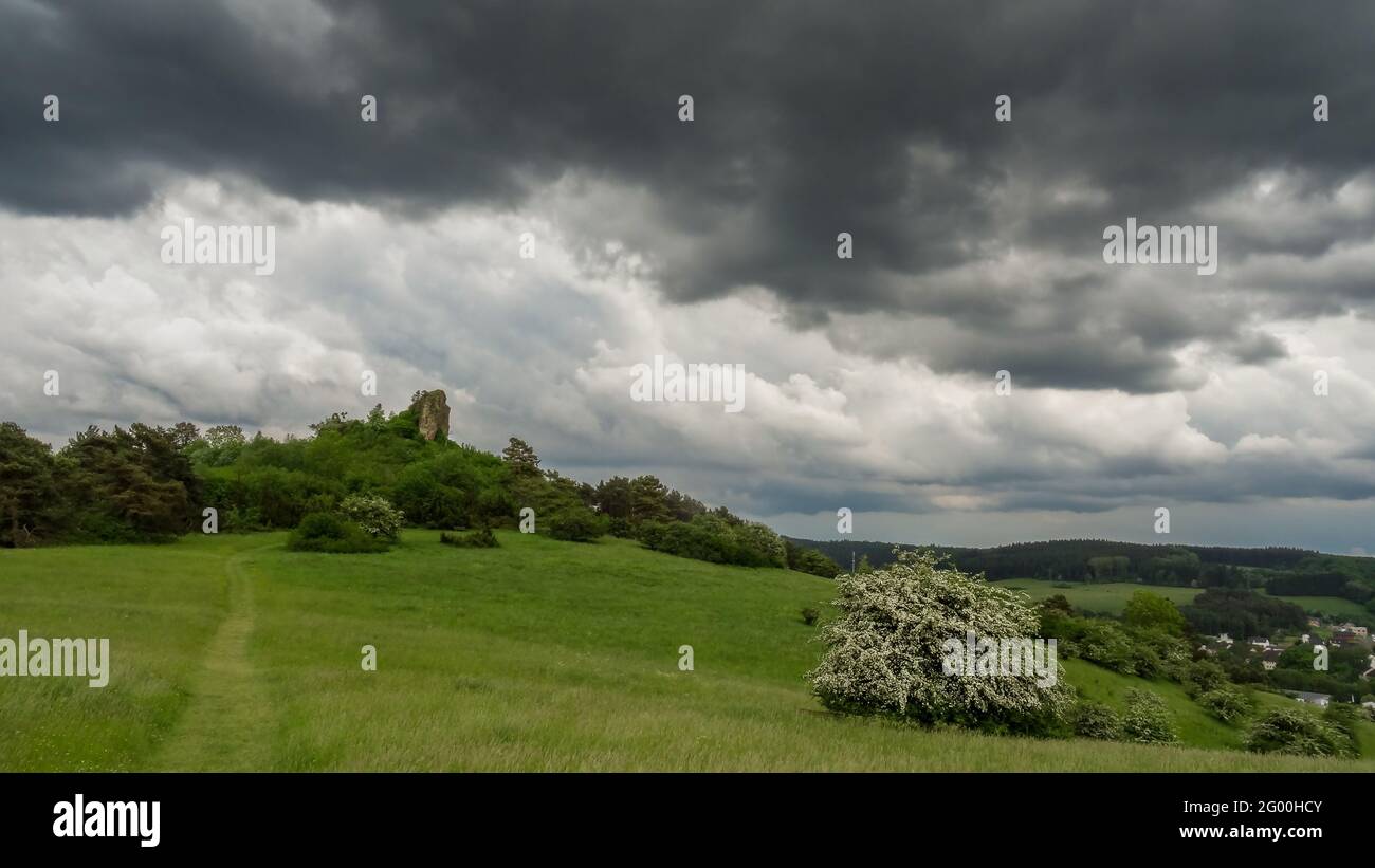 Eifel landscape with lone rock on green meadow with clouds of a summer ...