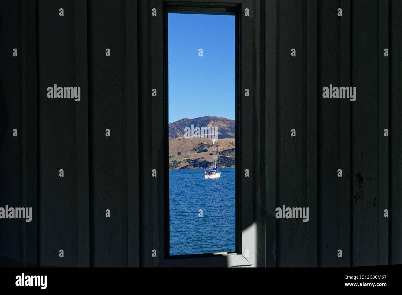 A yacht is anchored at sea, viewed through a narrow window, which ...