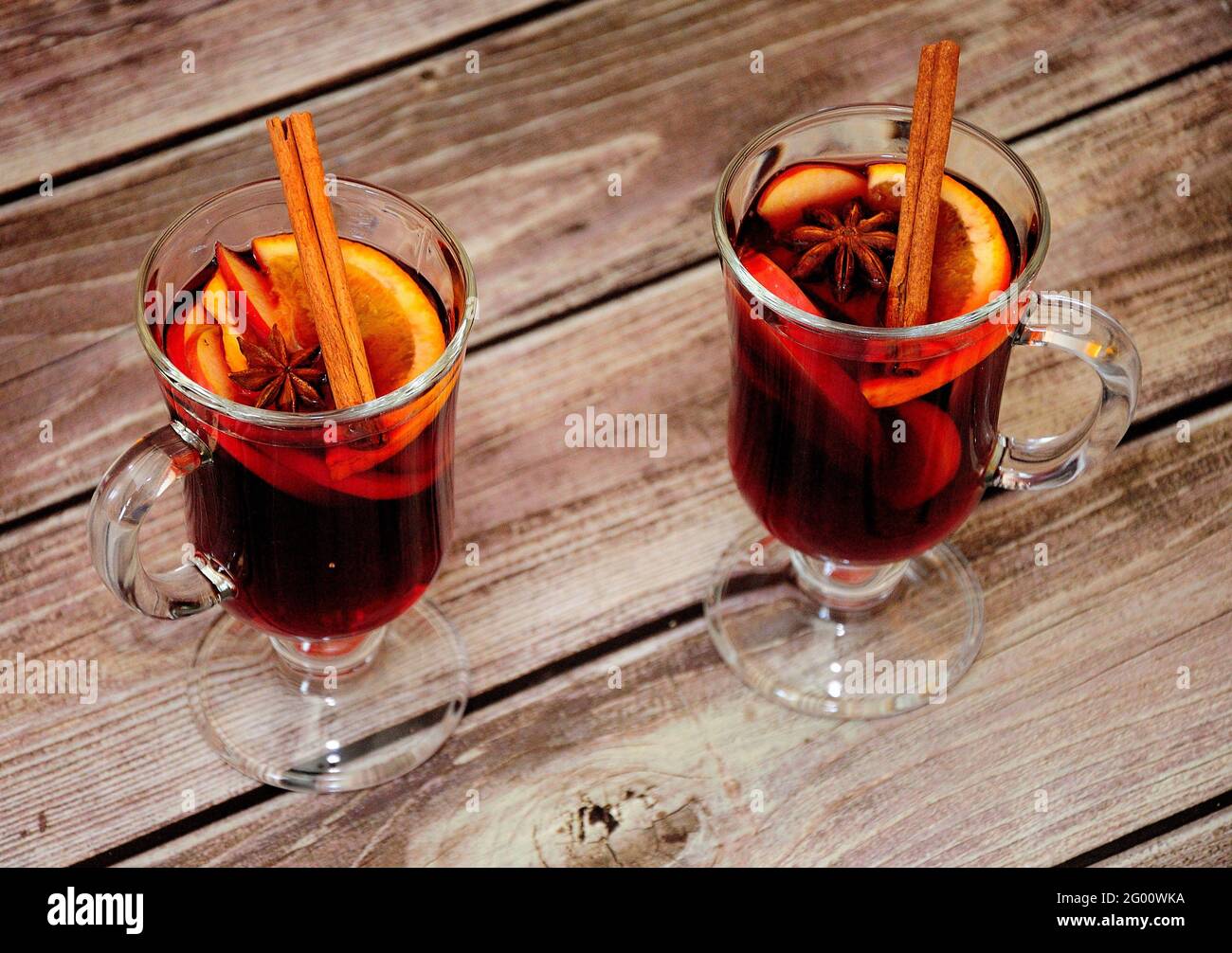 Two glasses of hot red wine with citrus fruits and spices stand on a ...