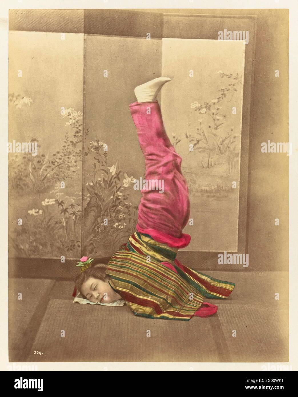 Japanese woman stands on her head and hands with legs perpendicular up ...