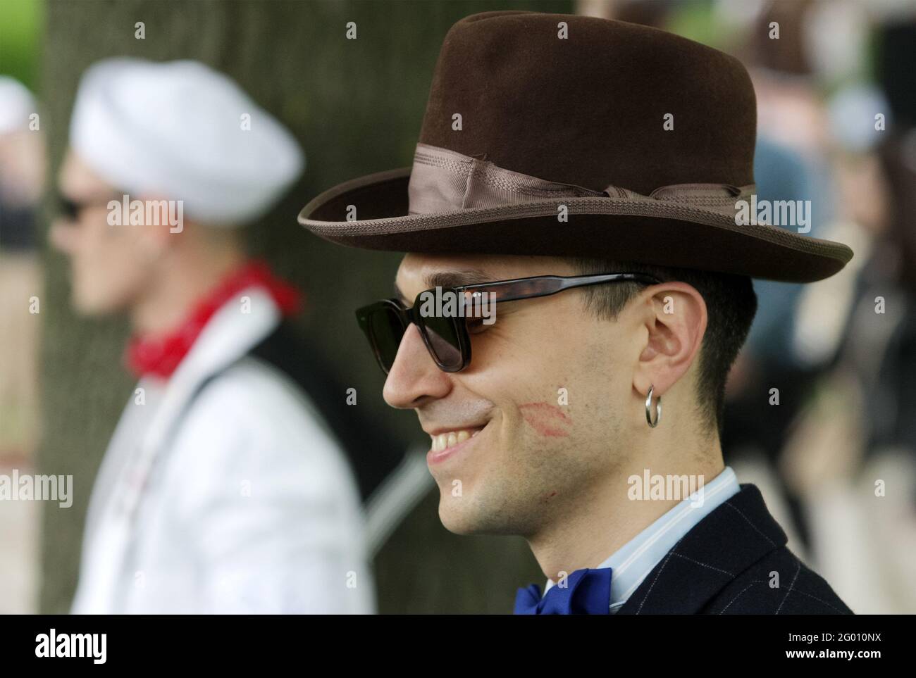A participant with a lipstick stain from a kiss on his cheek takes part during a retro cycle ...