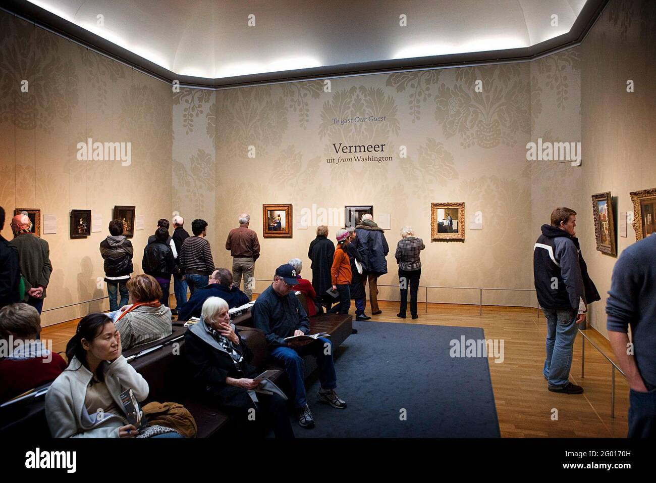 Room with paintings by Vermeer and standing and sitting visitors; Guest ...