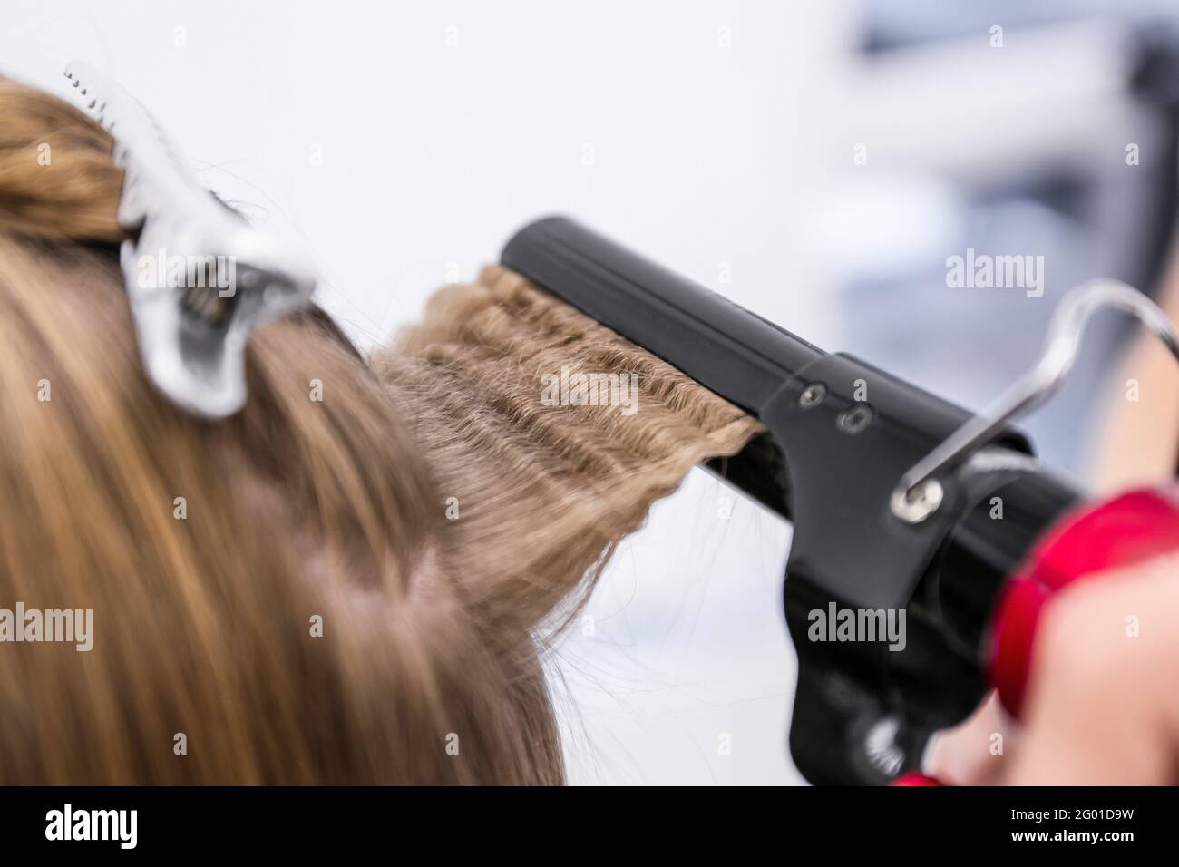 Female hairdresser curling hair of client in beauty salon, closeup ...