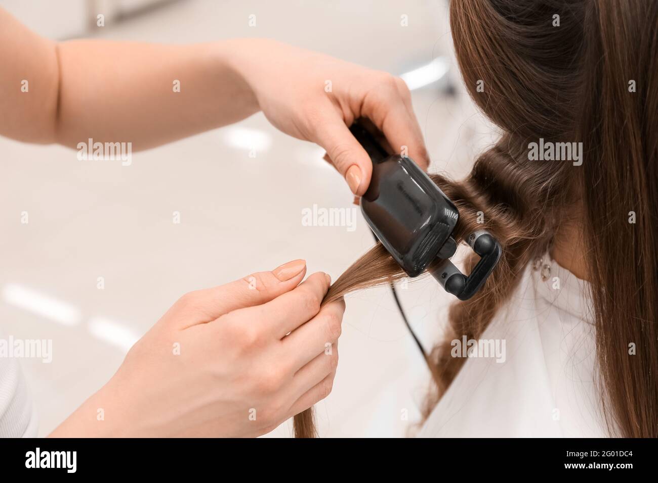 Female hairdresser curling hair of client in beauty salon, closeup ...