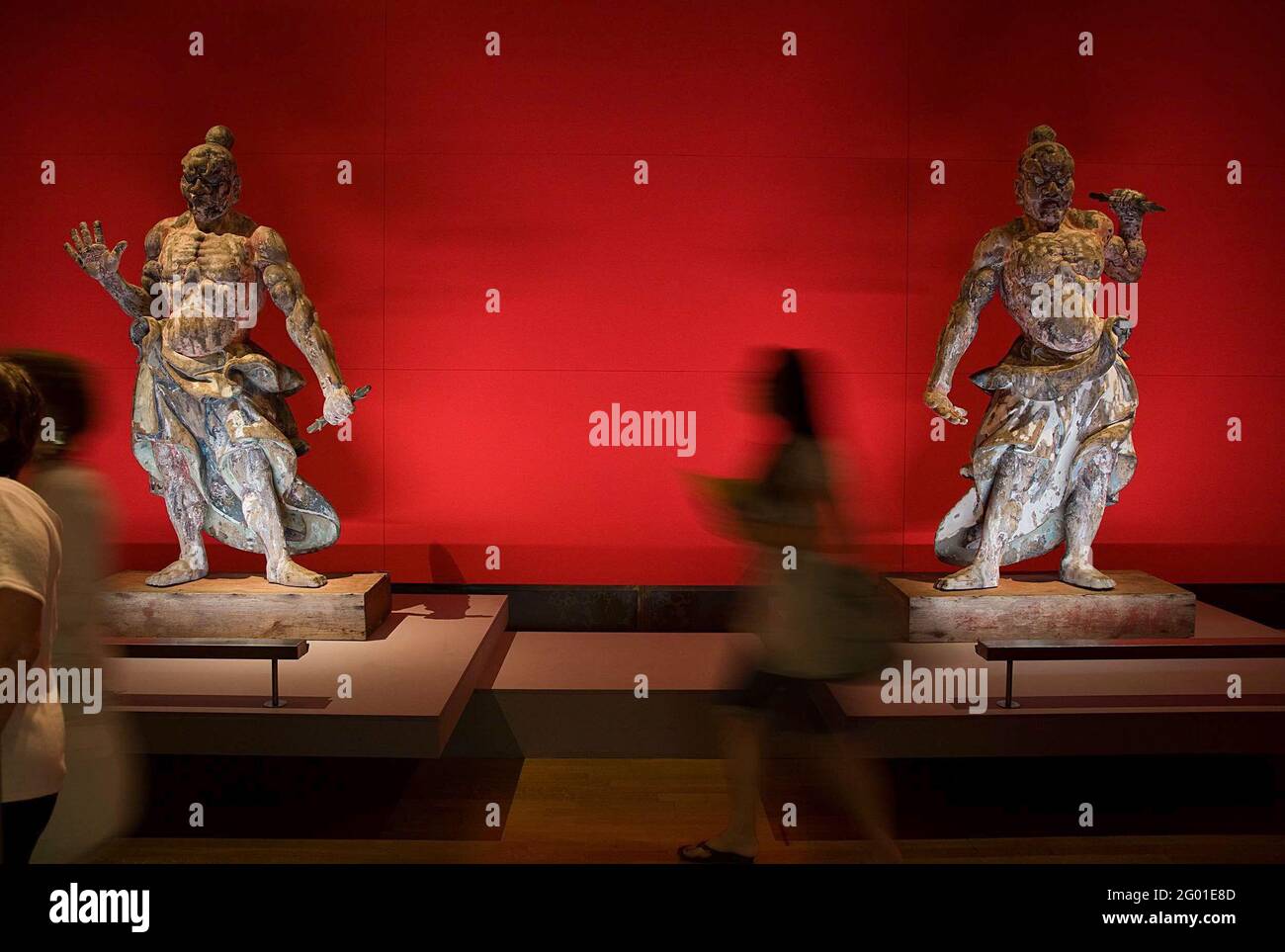 Visitors walking along two images of Japanese temple guards; Japanese ...