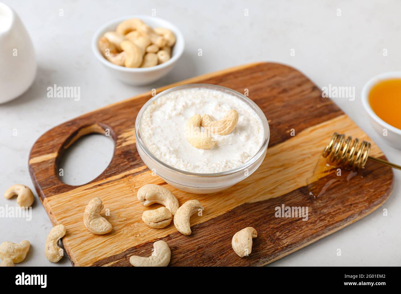 Bowl with cashew sour cream and nuts on light background Stock Photo ...