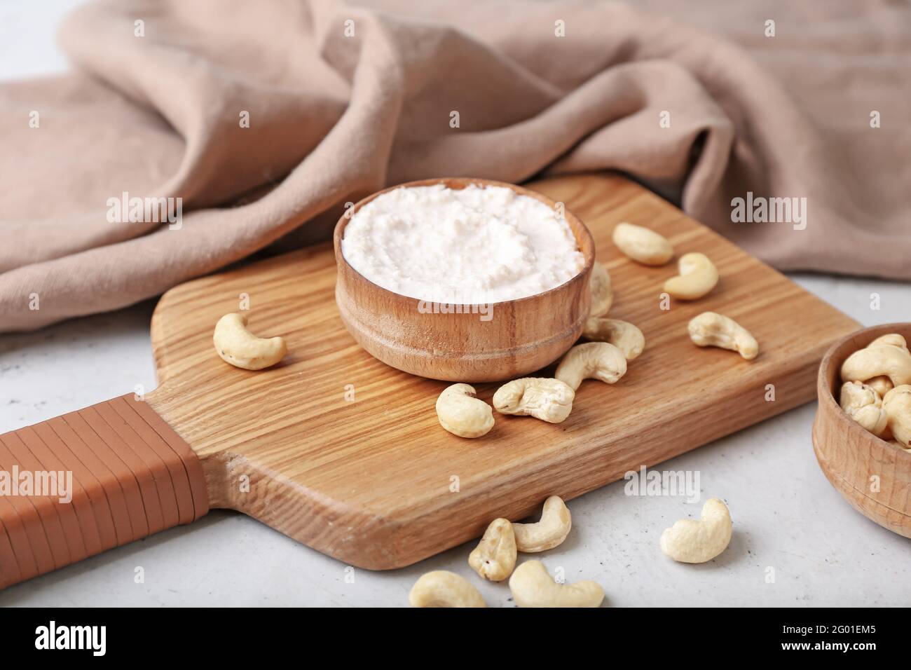 Bowl with cashew sour cream and nuts on light background Stock Photo ...