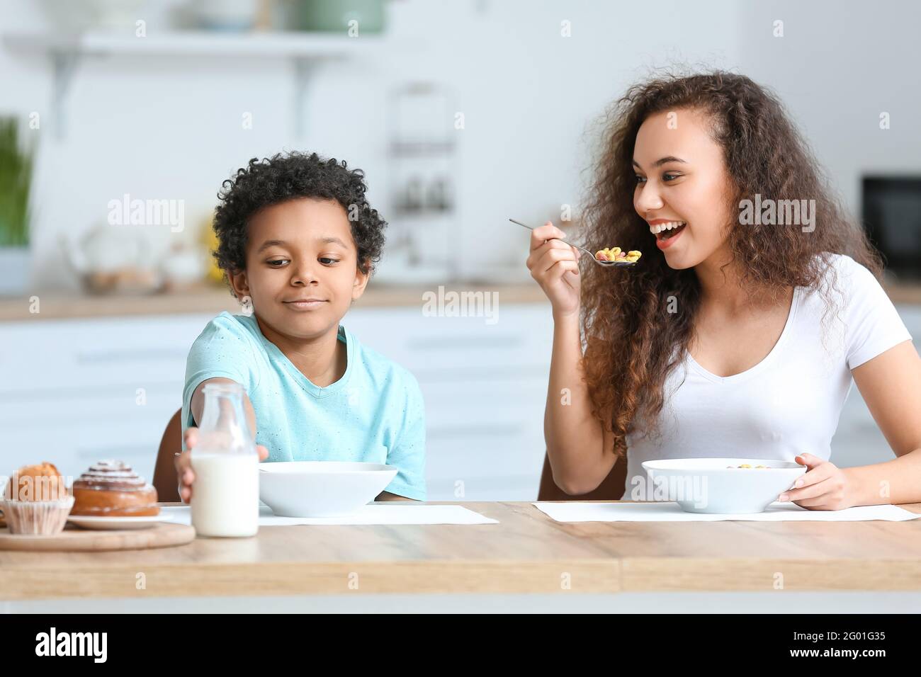 Little boy with mother eating cornflakes at home Stock Photo - Alamy